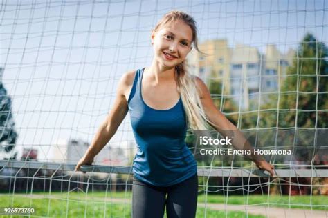 여자는 카메라와 블루 셔츠와 레 깅 스 스탠드 경기장에서 축구 목표 근처에서 일몰에 미소에 보인다 여자 완벽 한 그림을 그리고 좋은 모양 건강한 생활방식에 대한 스톡 사진