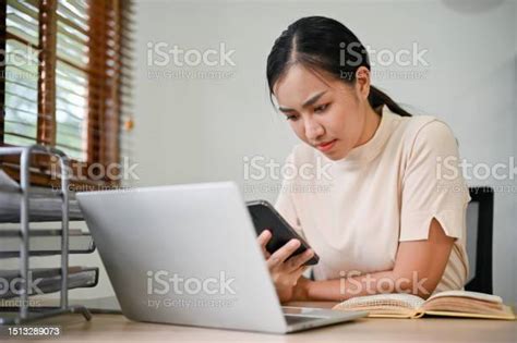 스마트폰과 노트북으로 집에서 일하는 스트레스가 많은 젊은 여성 25 29세에 대한 스톡 사진 및 기타 이미지 25 29세