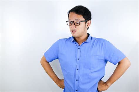 젊은 아시아 남자 입고 파란색 셔츠는 흰색 배경 위에 고립 된 카메라에서 소리지르고 손가락을 가리키는 재미있는 화가 얼굴입니다 20 29세에 대한 스톡 사진 및 기타 이미지