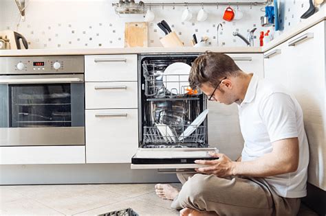 스마트 폰의 남자는 부엌에서 식기 세척기에 대한 지침을 봅니다 25 29세에 대한 스톡 사진 및 기타 이미지 25 29세 가구 가정 주방 Istock