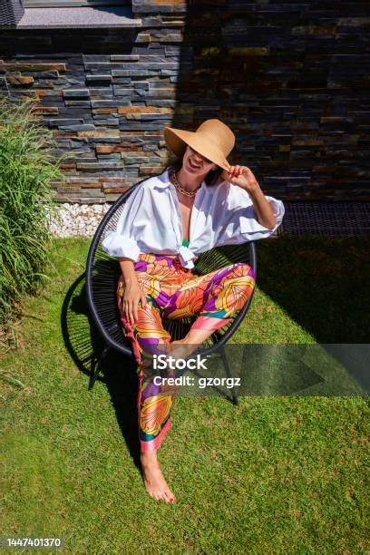 흰색 셔츠와 밀짚모자를 쓰고 정원의 라운지 의자에서 휴식을 취하는 매력적인 여성의 하이 앵글 샷 뒤뜰에 대한 스톡 사진 및 기타 이미지 Istock