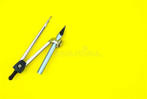 One Compass Attached To A Silver Color Wood Pencil Crayon On A Yellow