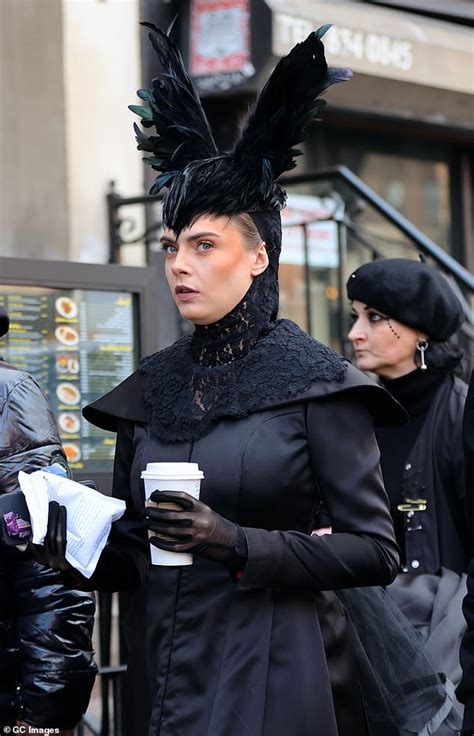 Cara Delevingne Dons A Feathered Headpiece And Dramatic Black Gown As She Is Spotted On The Set