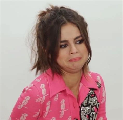 A Woman With Long Hair Wearing A Pink Shirt And Looking At The Camera While Standing In Front Of