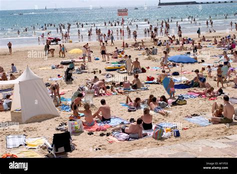 People On A White Sandy Beach Sun Tanning And Enjoying Themselves
