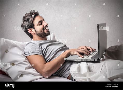Man Working On Laptop In Bed Stock Photo Alamy