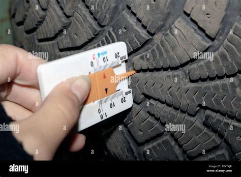 A Person Is Using A Ruler To Measure The Depth Of A Tire The Tire Is