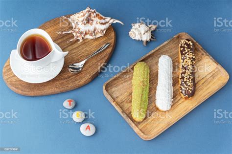나무 트레이에 세 개의 에클레어 근처 비문 차 차의 흰색 컵과 두 개의 바다 껍질 0명에 대한 스톡 사진 및 기타 이미지 0명 거품 내기 달콤한 음식 Istock