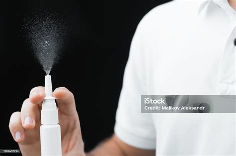 검은 색 배경에 흰색 셔츠를 입은 남자가 비강 스프레이를 확인합니다 나잘 스프레이에 대한 스톡 사진 및 기타 이미지 나잘