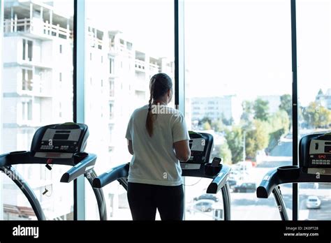 Fat Woman Run On Treadmill At Fitness Gym And Look Out Window At