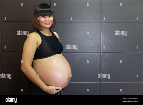 Portrait Of Pregnant Asian Woman Touching Her Big Belly Happily Stock