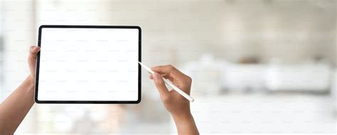 흐릿한 사무실 배경에서 스타일러스가 있는 빈 화면 태블릿을 사용하는 남자의 잘린 샷 사진 Unsplash의 사진술 이미지