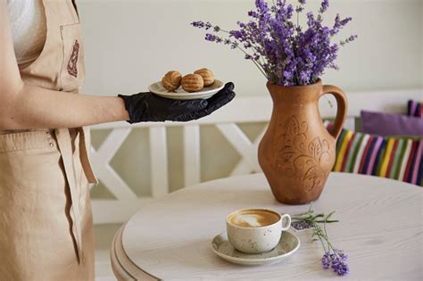 웨이터는 설탕이없는 채식주의 자 천연 견과류 과자를 제공합니다 카페의 나무 테이블에 카푸치노 컵 천연 과자 커피 브레이크 라벤더 장식 0명에 대한 스톡 사진 및 기타 이미지