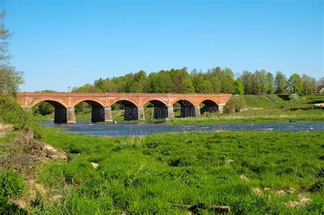 Historic Red Brick Arch Bridge Over River In Spring Landscape Stock