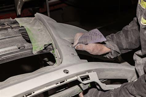 남자는 자동차 수리점에서 연마 종이의 도움으로 사고 후 그림에 대 한 차체 요소를 준비 합니다 충돌 후 복구 범퍼 교통사고 충돌