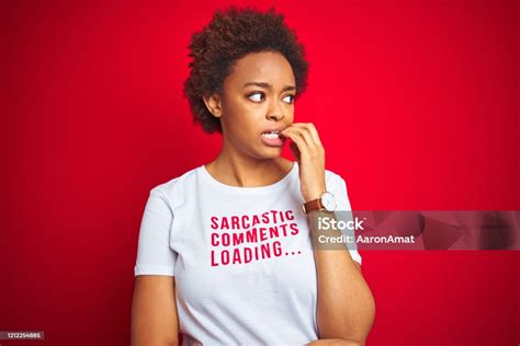 빨간 고립 된 배경 에 비꼬는 코멘트 티셔츠를 입고 아프리카 계 미국인 여성 스트레스와 긴장 한 입 물고 손톱에 손으로 불안 문제 T 셔츠에 대한 스톡 사진 및 기타 이미지