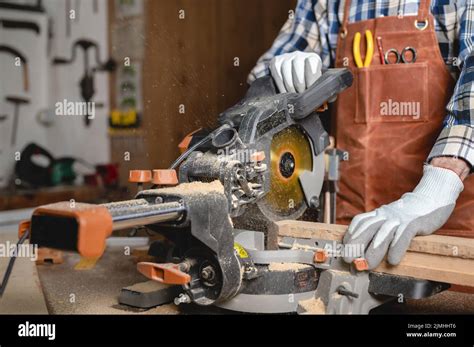 Carpenter Using An Electric Circular Saw Cutting Piece Of Wood Stock