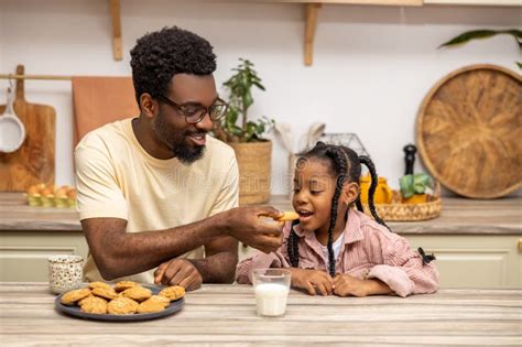 Feliz Pai Africano E Filha Comendo Biscoitos E Bebendo Cozinha De Leite