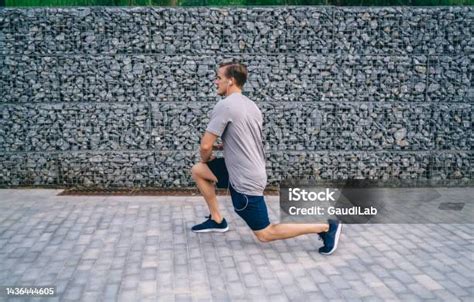 운동 중 거리에서 다리와 하체 근육을 스트레칭하는 스쿼트를 하는 강한 남성 운동선수 에너지를 얻기 위해 온난화 운동을 하는 거리에서 피트니스 훈련을 유지하는 백인 스포츠맨