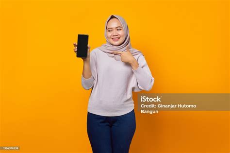 노란 배경을 통해 고립 된 스마트 폰 빈 화면을 보여주는 쾌활한 젊은 아시아 여성 25 29세에 대한 스톡 사진 및 기타 이미지 25 29세 Brand Name