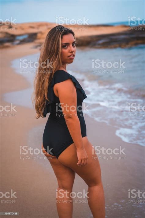 모래 해변에서 포즈를 취하는 검은 수영복을 입은 매력적인 백인 여성의 얕은 초점 샷 관능에 대한 스톡 사진 및 기타 이미지