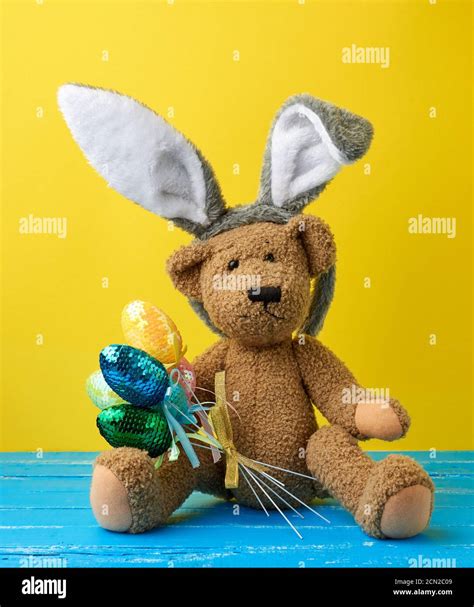 Cute Brown Teddy Bear Holding Colorful Easter Eggs Wearing A Rabbit