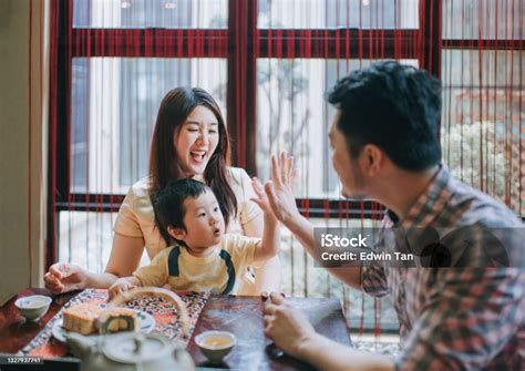 중국 인 아버지와 함께 아들과 함께 한 하이파이브는 전통 중한가을 달케이크와 애프터눈 티 모임 중 집에서 중국 차를 즐기며 Mid Autumn Festival에 대한 스톡