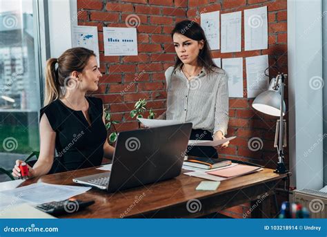 Young Personal Assistant Discussing Plans With Boss In Her Office Stock