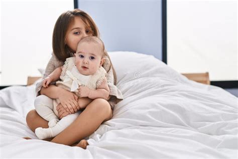 Brother And Sister Hugging Each Other Sitting Together On Bed At