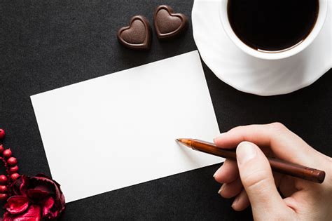 여자의 손을 흰색 빈 인사말 카드에 쓰기 어두운 테이블에 초콜릿 마음으로 블랙 커피 한잔 축 하 개념입니다 좋은 분위기의 텍스트에 대 한 빈 장소입니다 감사에 대한 스톡