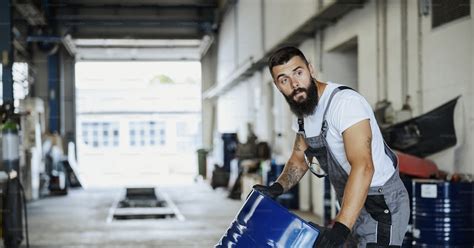 제복을 입은 노동자가 배럴을 굴려 다른 작업장으로 옮깁니다 작업장에서 배럴을 굴리는 작업자 사진 Unsplash의 통 이미지