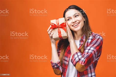 웃는 젊은 아름 다운 여자의 스튜디오 초상화는 빨간 선물 상자를 보유 하 고 있습니다 오렌지 배경에 고립 매우 기쁜에 대한 스톡