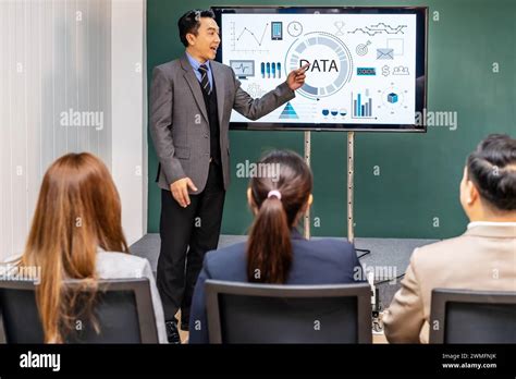 a man presenting company data on a big screen with charts and graphs
