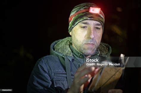 Explorer Traveler Man Consults His Map And Notes During Night Walk
