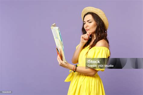 노란 드레스에 잠겨있는 젊은 여자 여름 모자 개최 도시 지도 파스텔 바이올렛 벽 배경에 고립 된 여권 탑승권 티켓 사람들은 진심으로 감정 라이프 스타일 개념입니다 복사