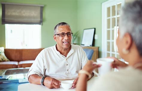 커피를 마시고 휴식을 취하고 아침에 집에서 함께 식탁에 앉아 이야기를 나누는 시니어 커플 행복하고 미소 짓는 노인 남녀가 집에서 은퇴 후 차와 함께 의사 소통을 하고