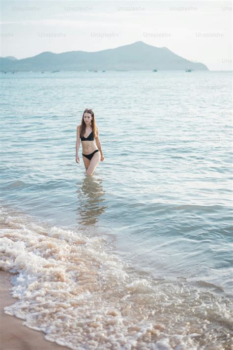 검은 비키니를 입은 아름다운 여자가 바다에서 걷고 있다 여름 개념 사진 Unsplash의 개념 이미지