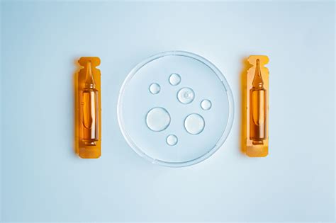 갈색 플라스틱 앰플의 헤어 케어 오일 또는 세럼 또는 페트리 접시에 오일 샘플이있는 파란색 배경의 캡슐 제품 마케팅 모형 컨셉 뷰티 헤어 셀프 케어 및 웰빙 0명에 대한