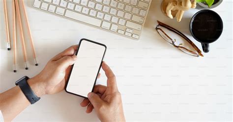 데스크톱 컴퓨터 사무용품 커피 머그잔이 있는 사무실 흰색 책상 테이블에서 휴대폰을 사용하는 남자 평면도 작업 공간 및 빈