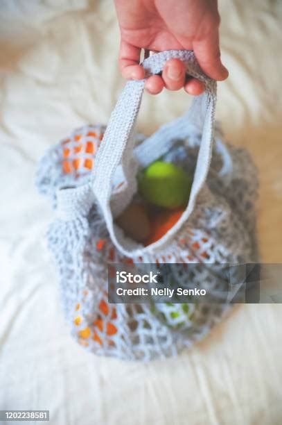 남성 손은 끈 가방을 클로즈업하고 공간을 복사합니다 에코 백제로 폐기물 제로 구겨진 패브릭에 오렌지와 사과를 곁들인 메쉬 쇼핑백