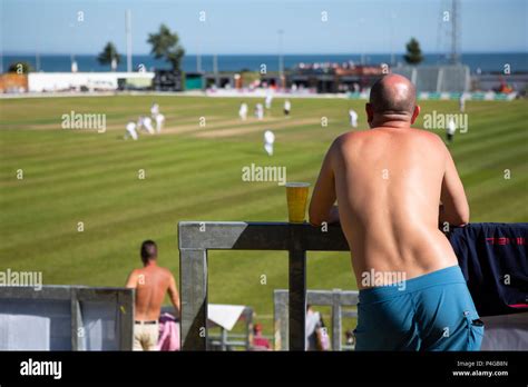 A Topless Spectator Enjoys A Cold Beer On A Hot Day Watching Cricket In
