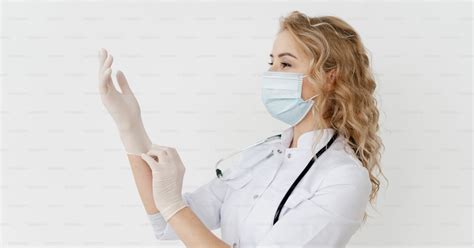 의료 유니폼을 입고 수술용 장갑을 끼고 보호용 안면 마스크를 쓴 여성 의사 병원의 복사 공간 벽에 청진기를 들고 서 있다 클리닉 의료의 개념 사진 Unsplash의