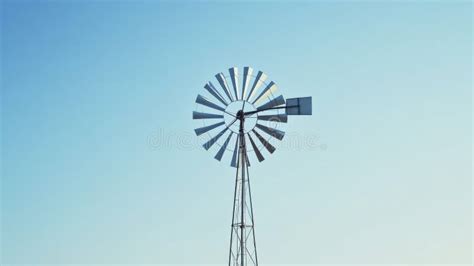 Metal Windmill Rotating Against A Clear Blue Sky Stock Illustration