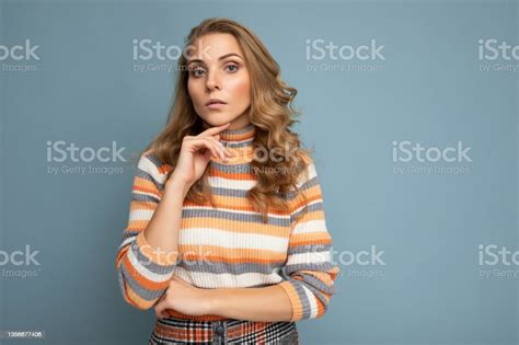 텍스트빈 공간과 파란색 배경 위에 고립 된 줄무늬 스웨터를 입고 물결 모양의 머리를 가진 젊은 예쁜 아름다운 매력적인 진지한