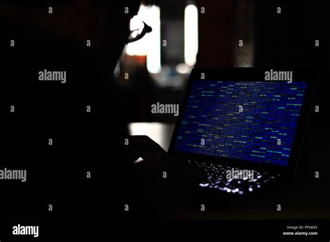 computer hacker silhouette typing on computer in a dark room working