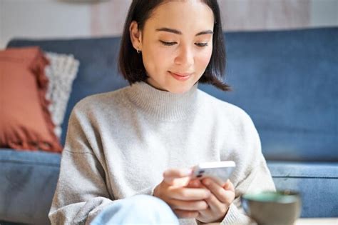 Premium Photo Young Woman Using Mobile Phone While Sitting On Sofa At