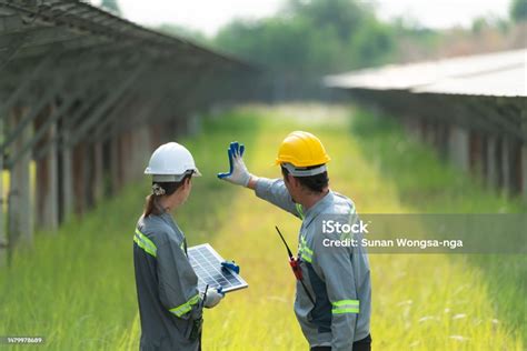 태양 전지판이 있는 수백 에이커의 잔디에서 전력 엔지니어 팀이 이 분야에 설치된 소형 태양 전지판의 프로토타입을 테스트하고 있습니다 2명에 대한 스톡 사진 및 기타 이미지