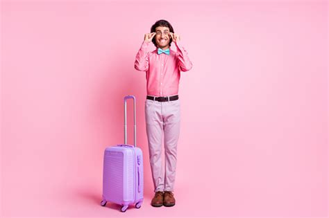 풀 사이즈 사진 의 잘 생긴 브루넷 트렌디 한 젊은 신사 홀드 안경 수하물 절연 에 파스텔 핑크 컬러 배경 수하물에 대한 스톡