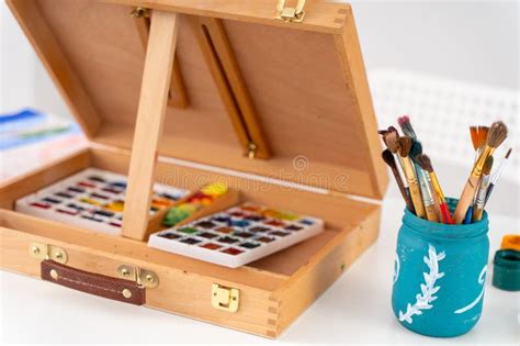Easel With Watercolors And Art Brushes On A White Table Artist S