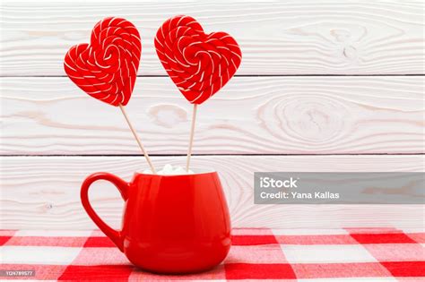 발렌타인 데이 배경 두 개의 심장 모양의 흰색 나무 바탕에 체크 무늬 식탁보에 빨간색 컵에 막대 사탕 개념에 대한 스톡 사진 및